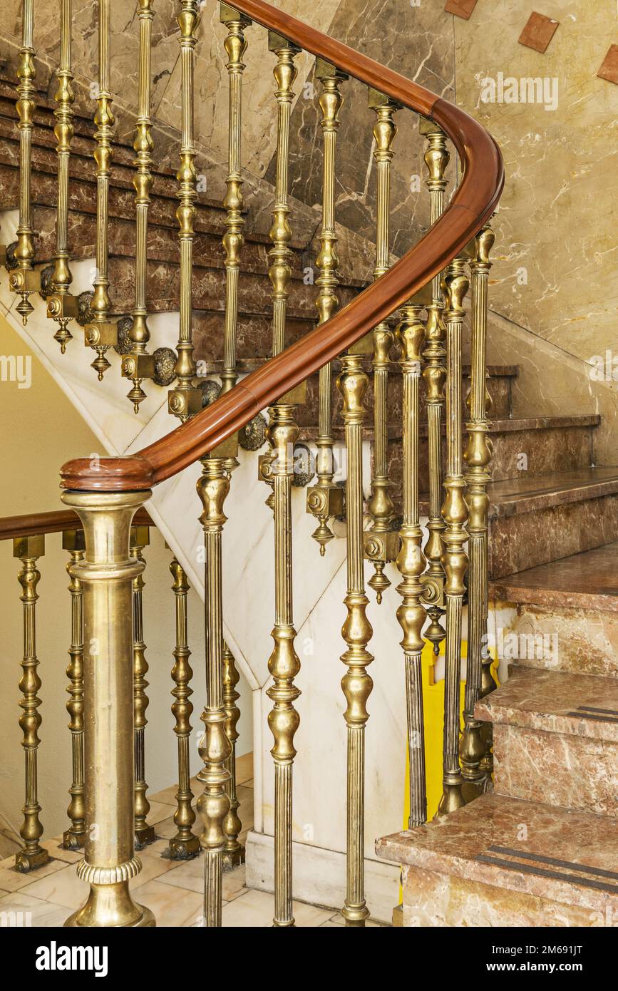 Detail of a golden metal marble staircase railing with a varnished ...
