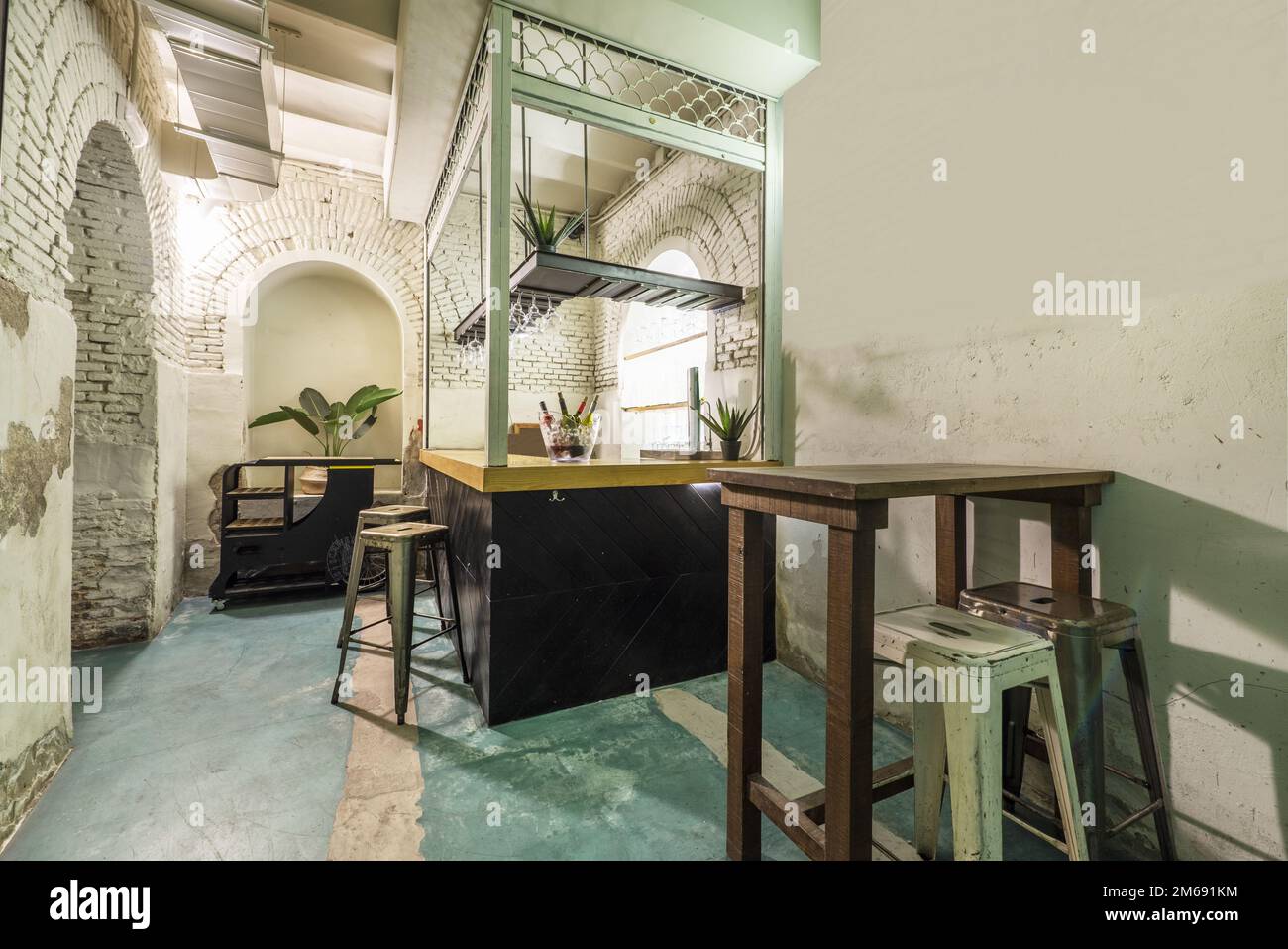 Counter of a bar with high metal stools and matching wooden tables ...