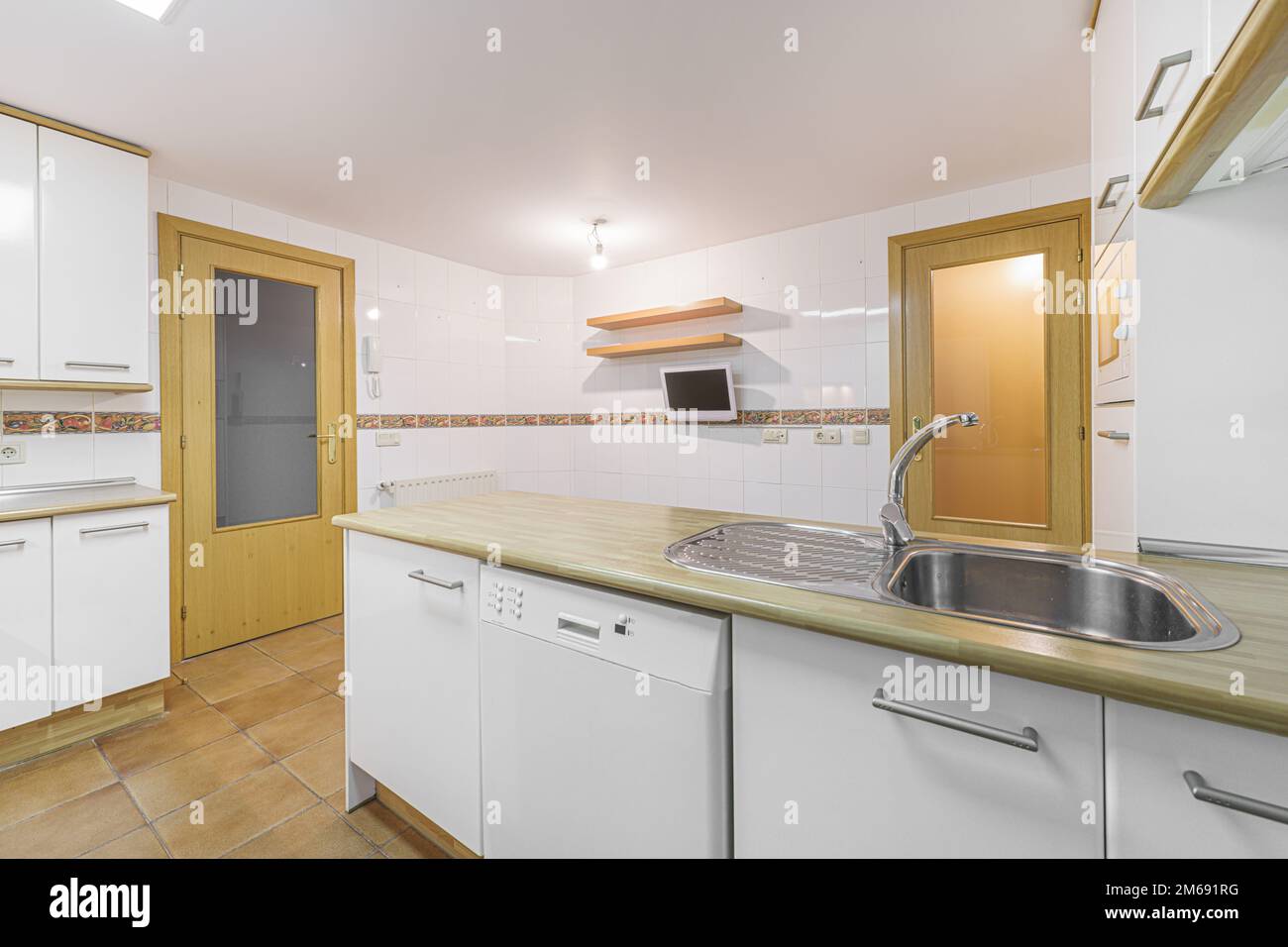 Island of a conventional kitchen with white wooden cabinets with steel ...