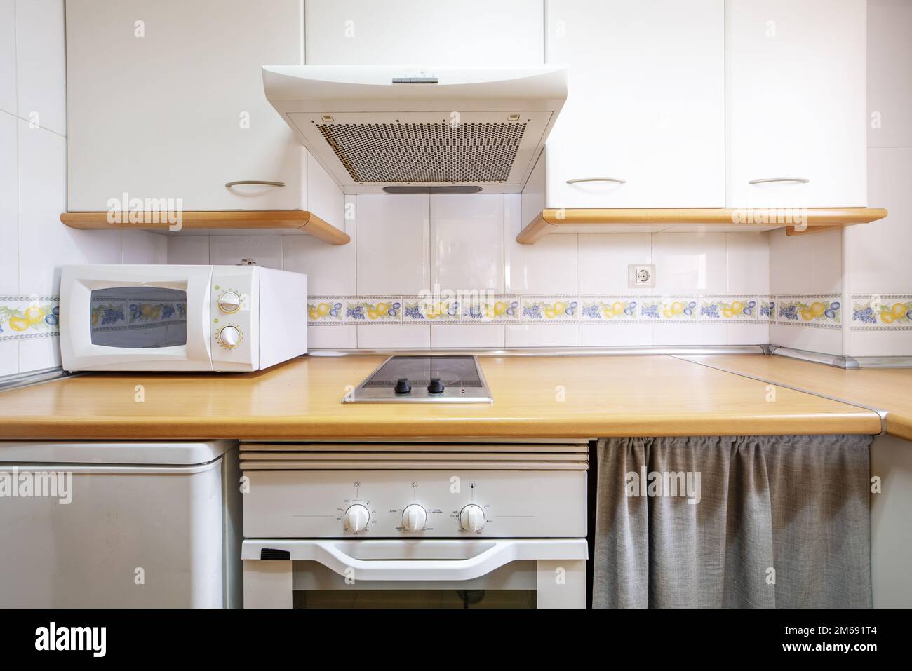 Front image of a kitchen furnished with white cabinets and a wooden ...