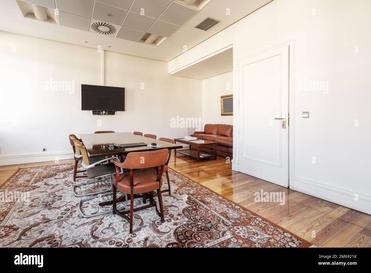 Office with a boardroom table on a rug in matching tones and a brown ...