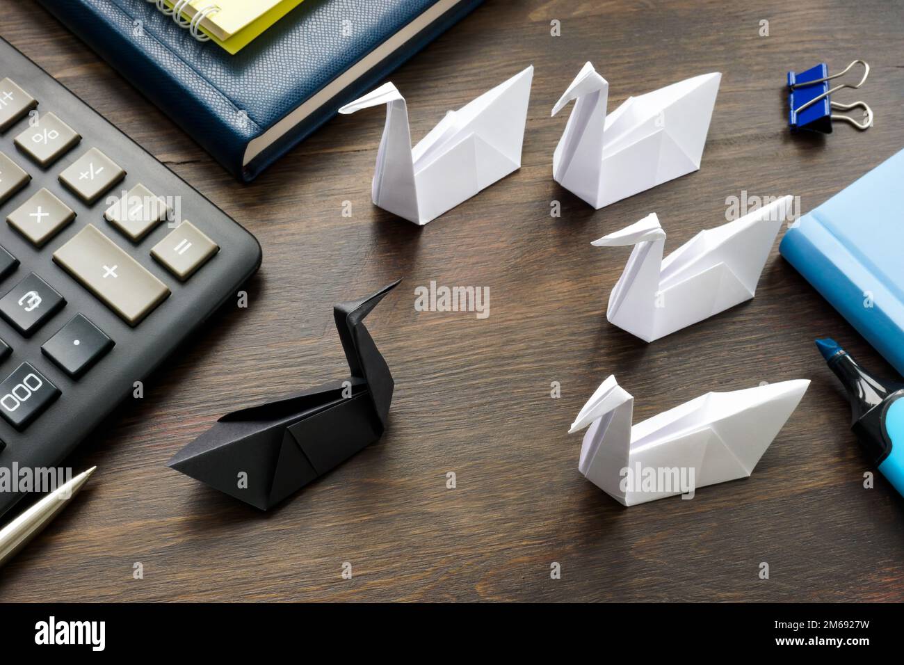 Paper black swan and white ones on the office table as unpredictable ...