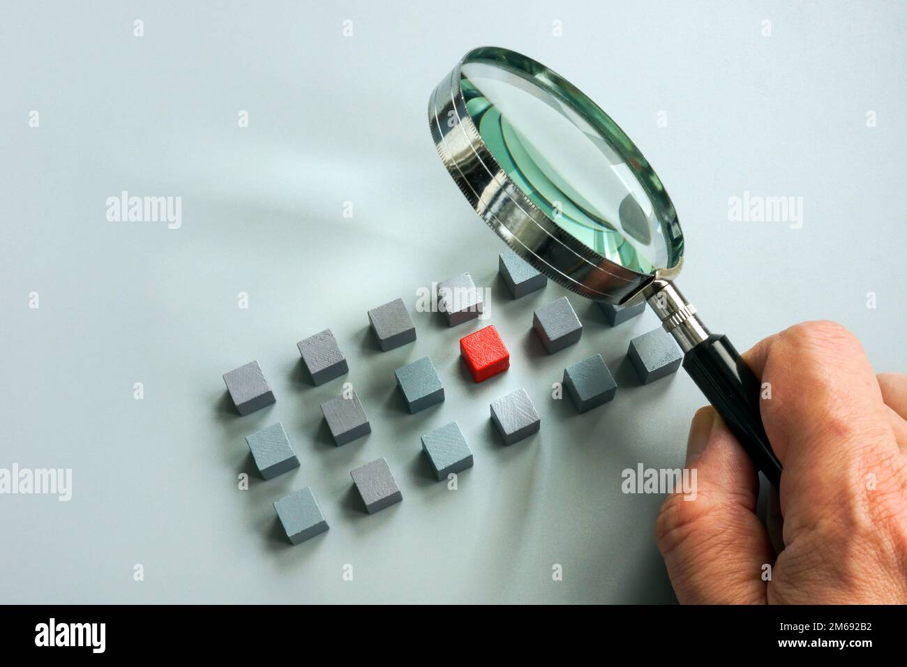 Talent management concept. A hand with a magnifying glass over gray ...