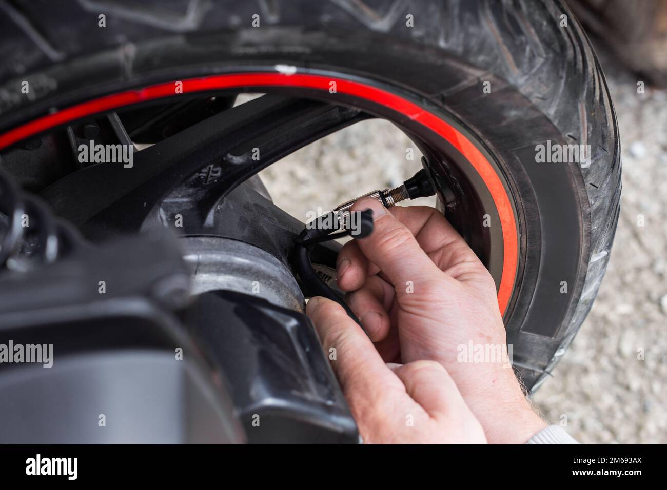 A man inflates a tire on a motorcycle with an air compressor ...