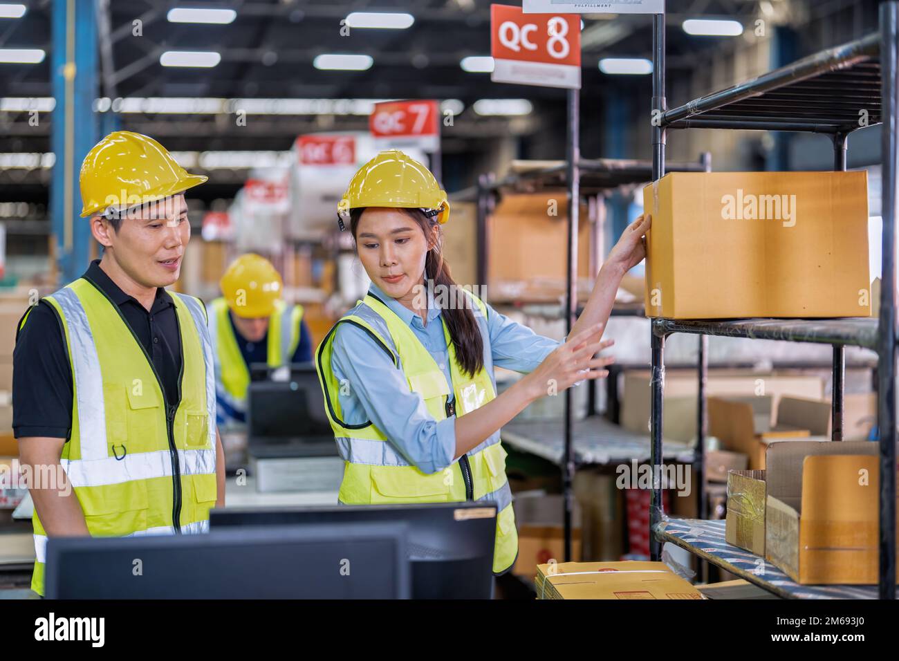 Staff working in large depot storage warehouse trainee check packing ...