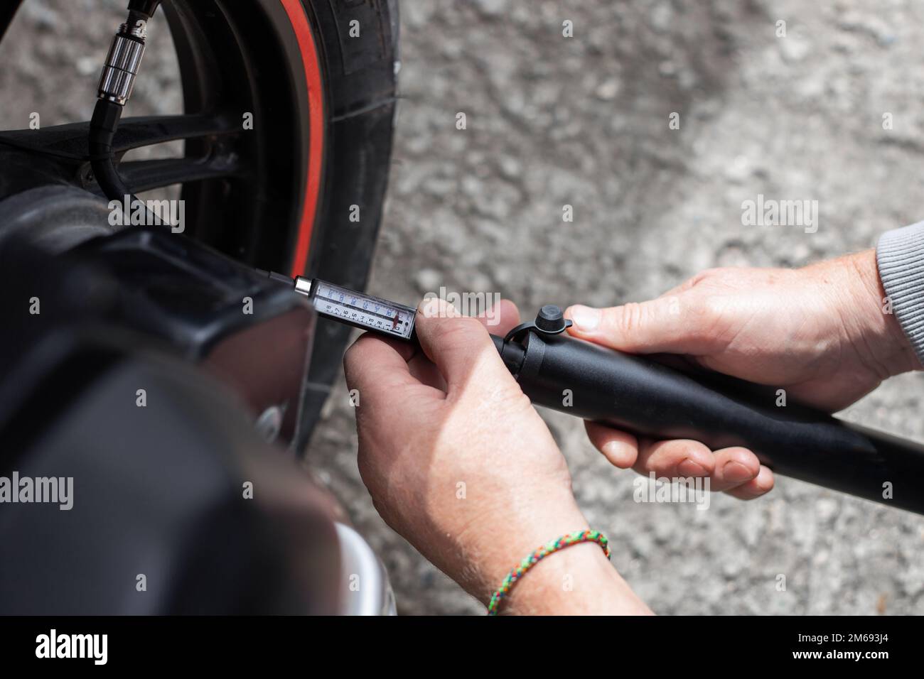 A man inflates a tire on a motorcycle with an air compressor ...