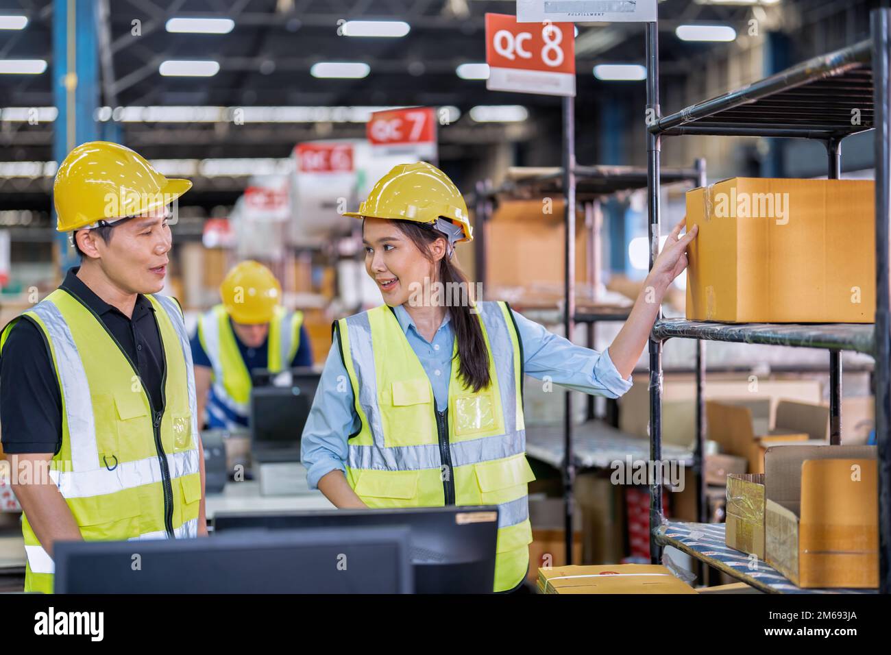 Staff working in large depot storage warehouse trainee check packing ...