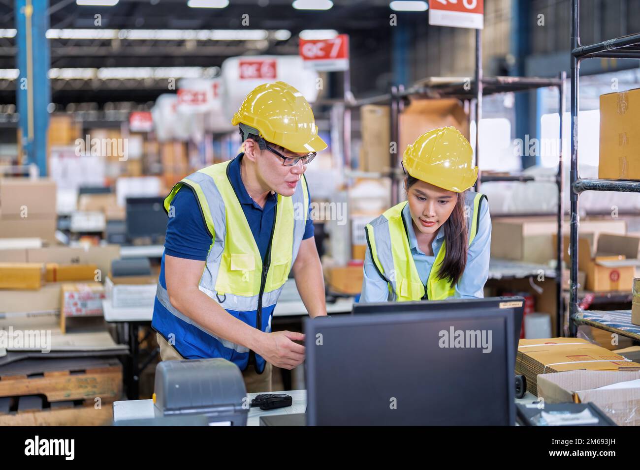 Staff working in large depot storage warehouse trainee check packing ...