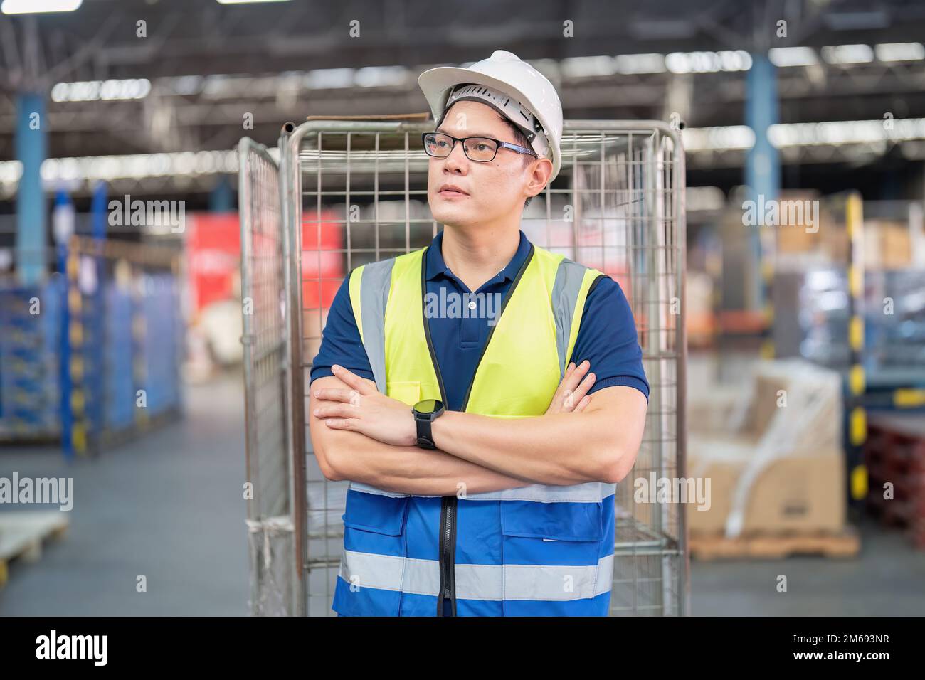 Staff working in large depot storage warehouse push manual trolley ...