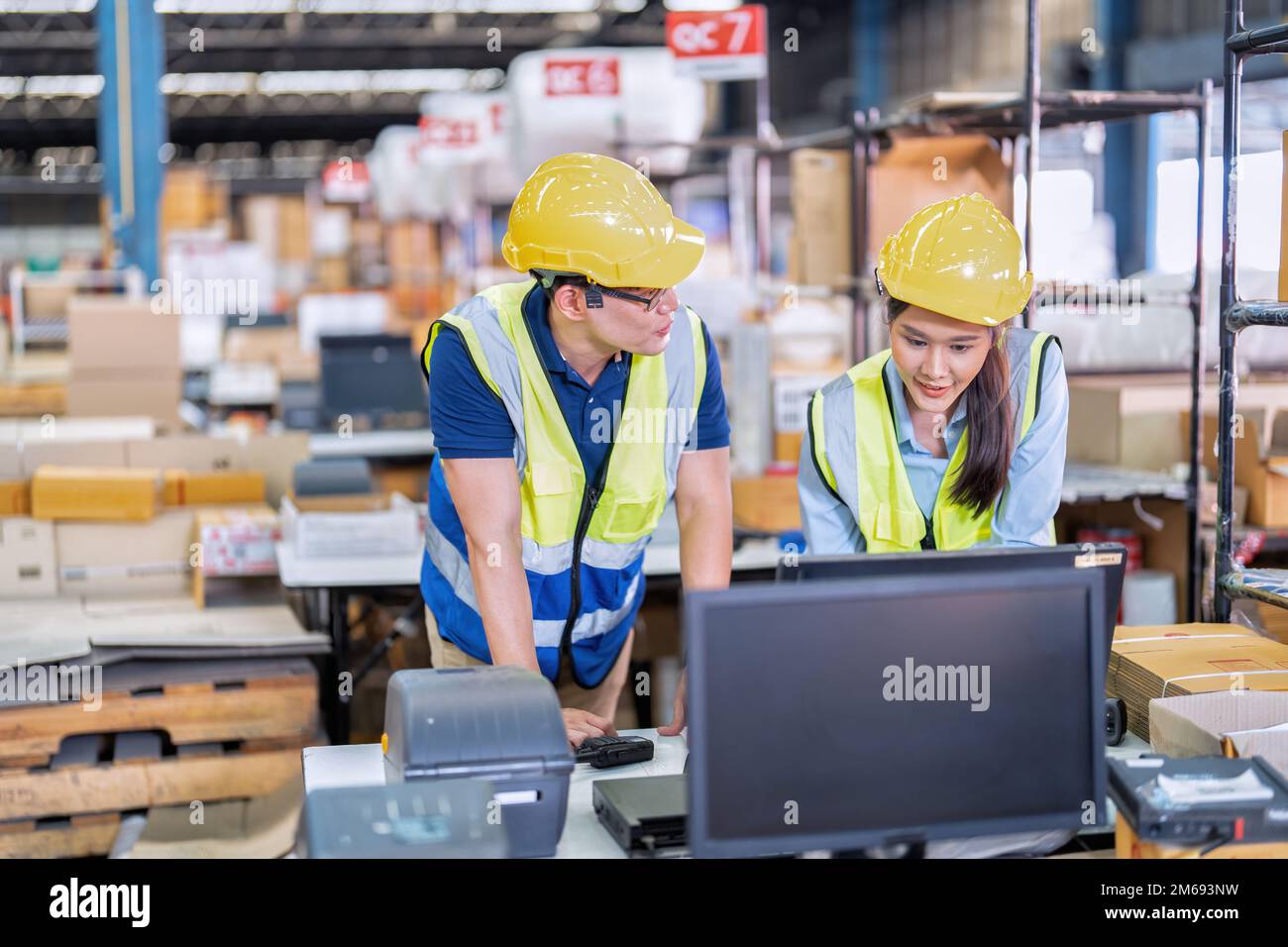 Staff working in large depot storage warehouse trainee check packing ...