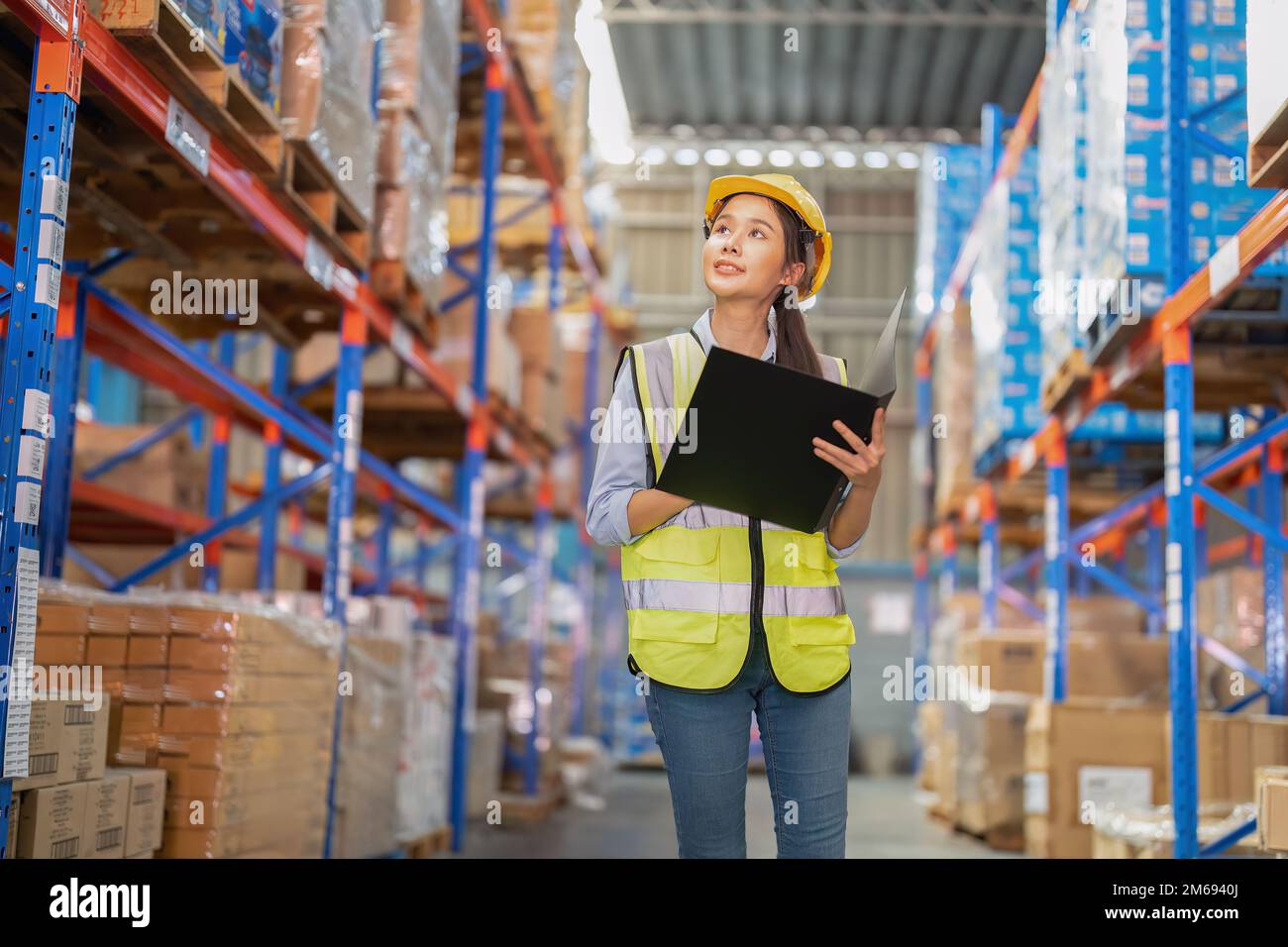 Staff working in large depot storage warehouse hold check list walking ...