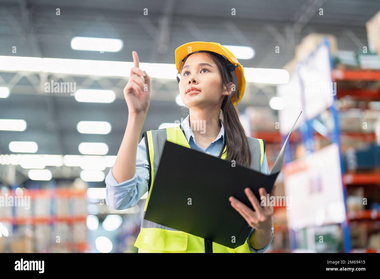 Staff working in large depot storage warehouse hold check list walking ...