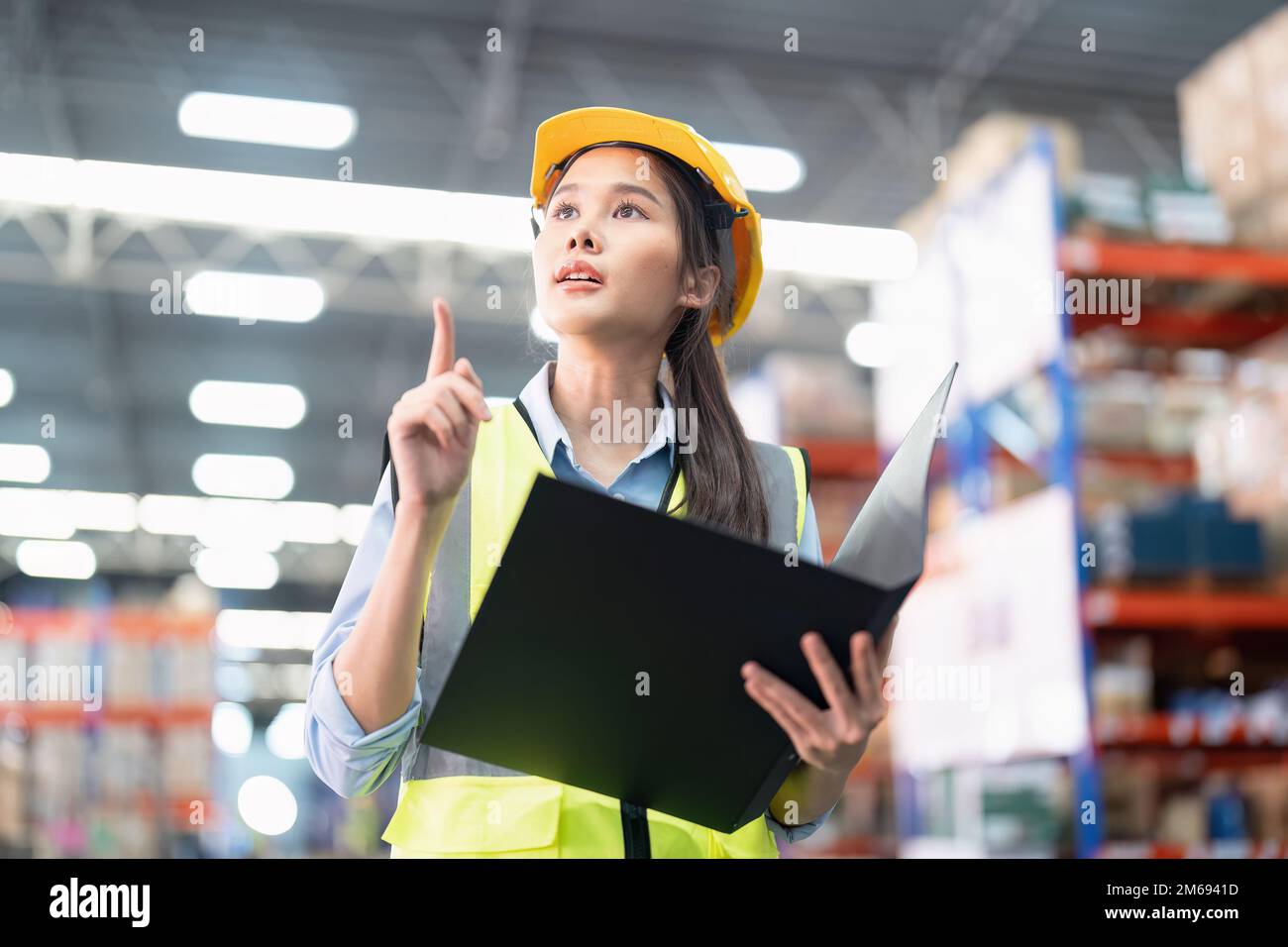 Staff working in large depot storage warehouse hold check list walking ...