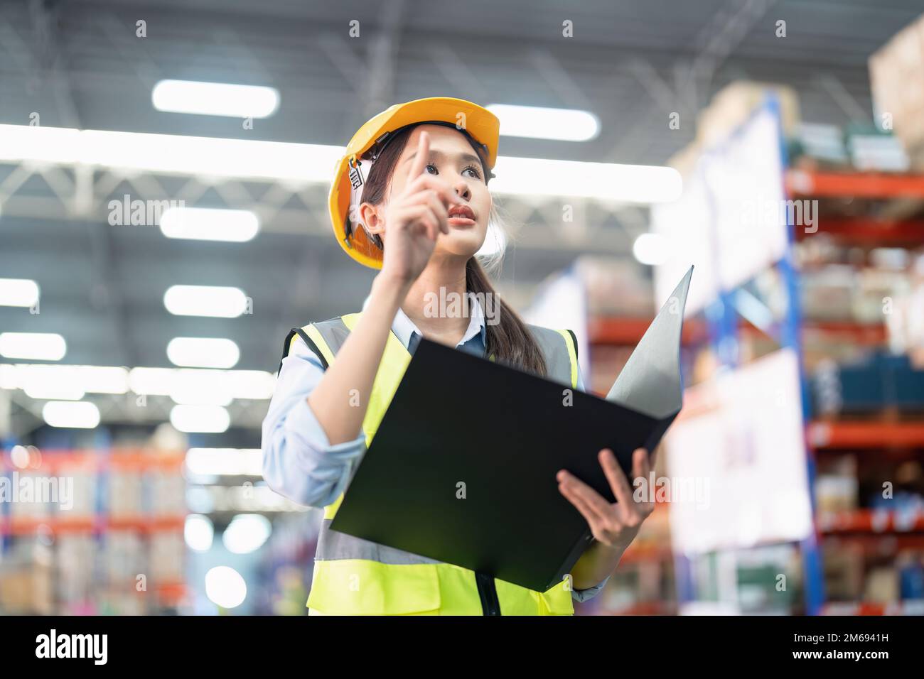 Staff working in large depot storage warehouse hold check list walking ...