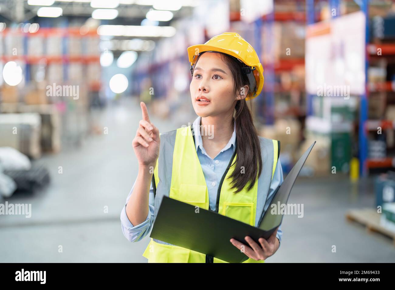 Staff working in large depot storage warehouse hold check list walking ...