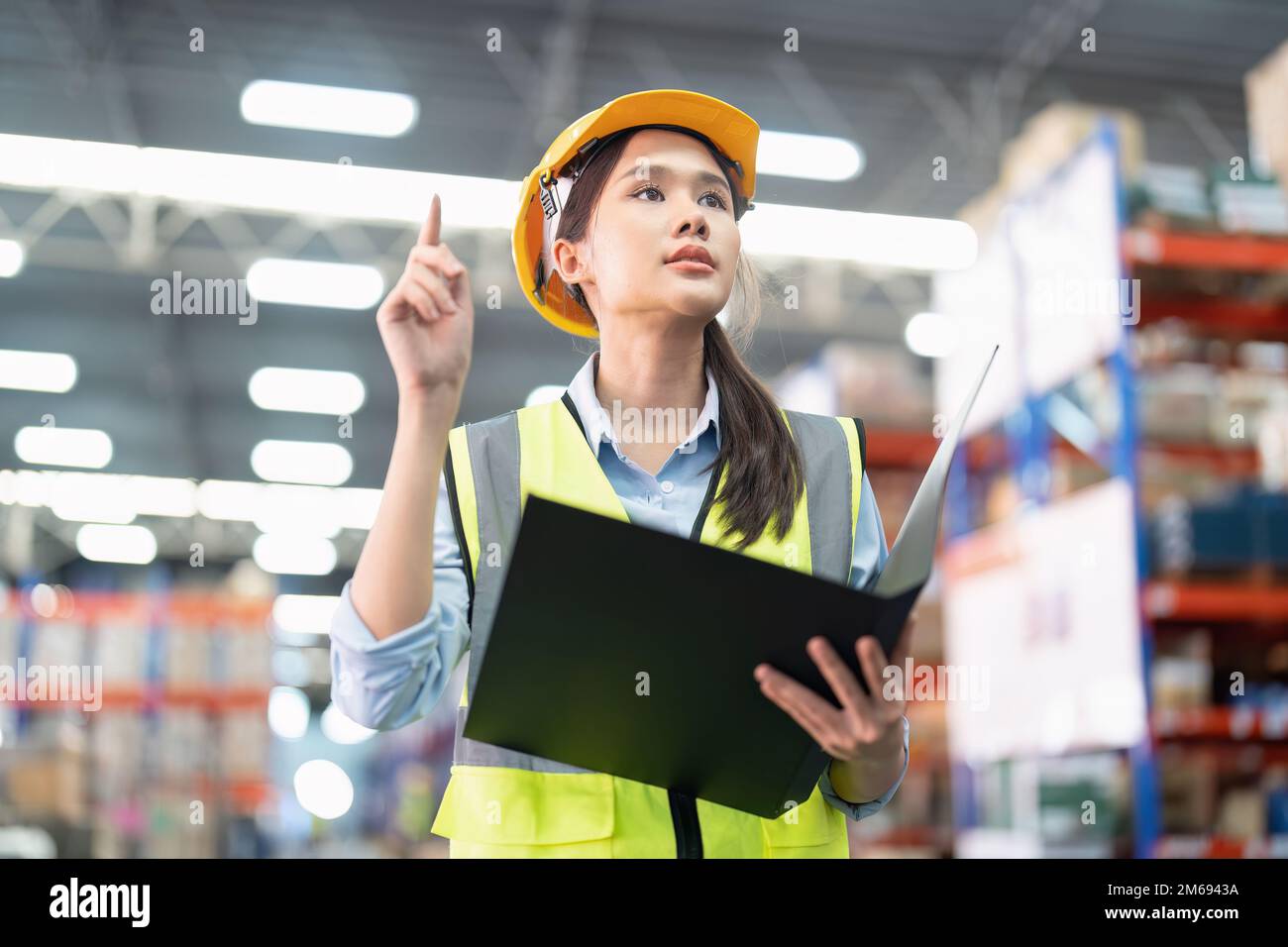 Staff working in large depot storage warehouse hold check list walking ...