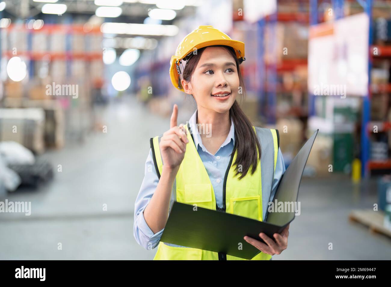 Staff working in large depot storage warehouse hold check list walking ...