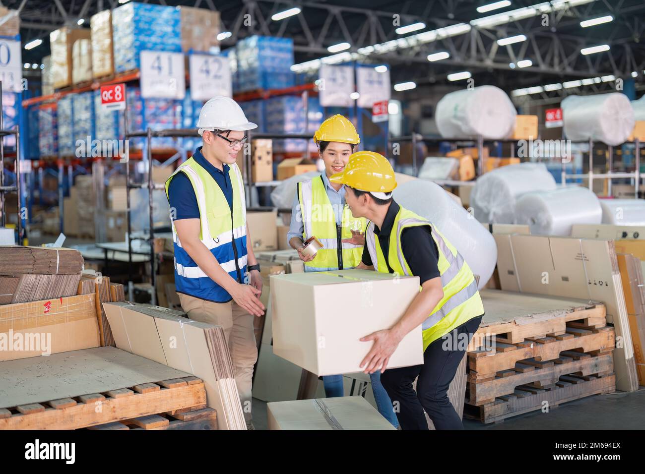 Staff in large storage warehouse together packing goods and carry ...