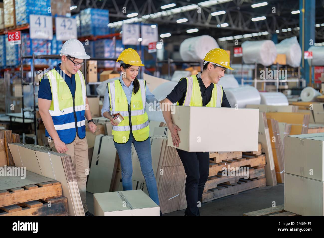 Staff in large storage warehouse together packing goods and carry ...