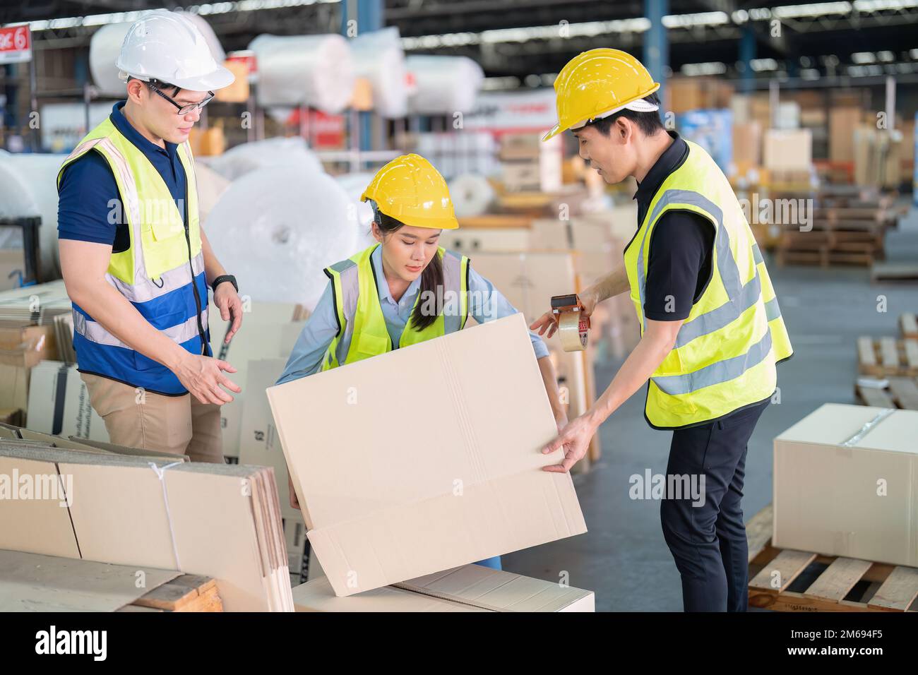 Staff in large storage warehouse together packing goods and carry ...