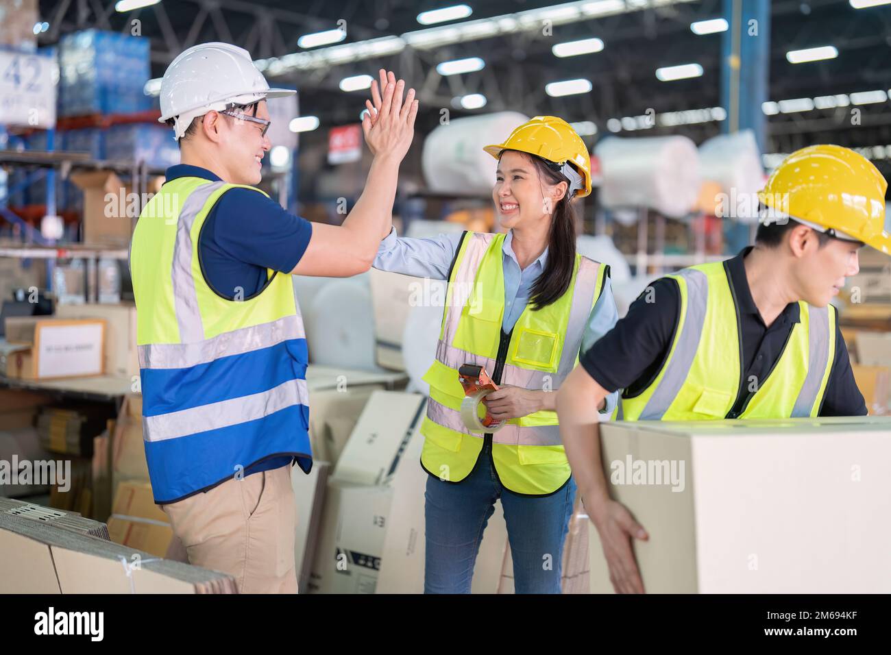 Staff in large storage warehouse together packing goods and carry ...