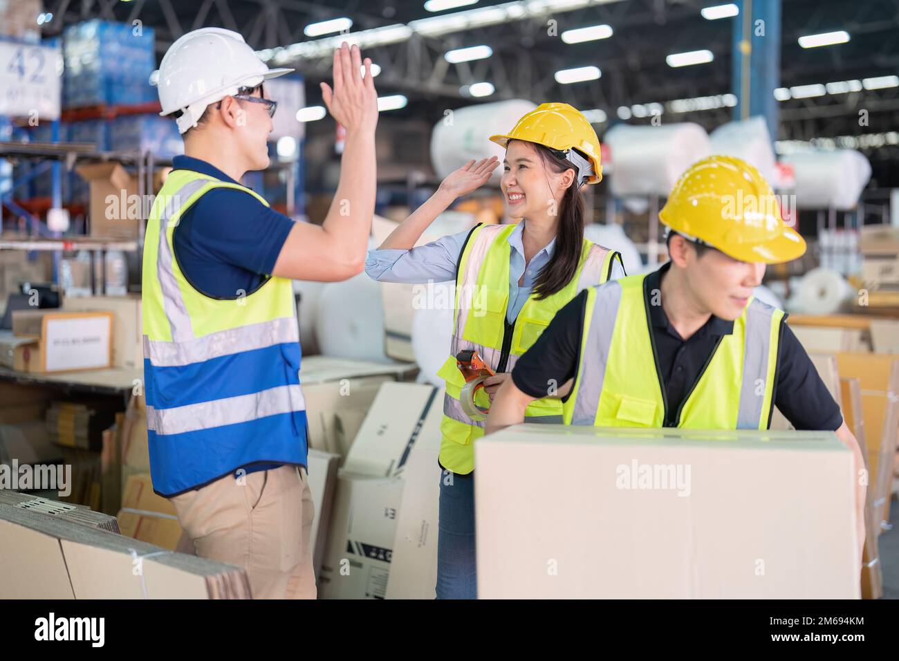 Staff in large storage warehouse together packing goods and carry ...