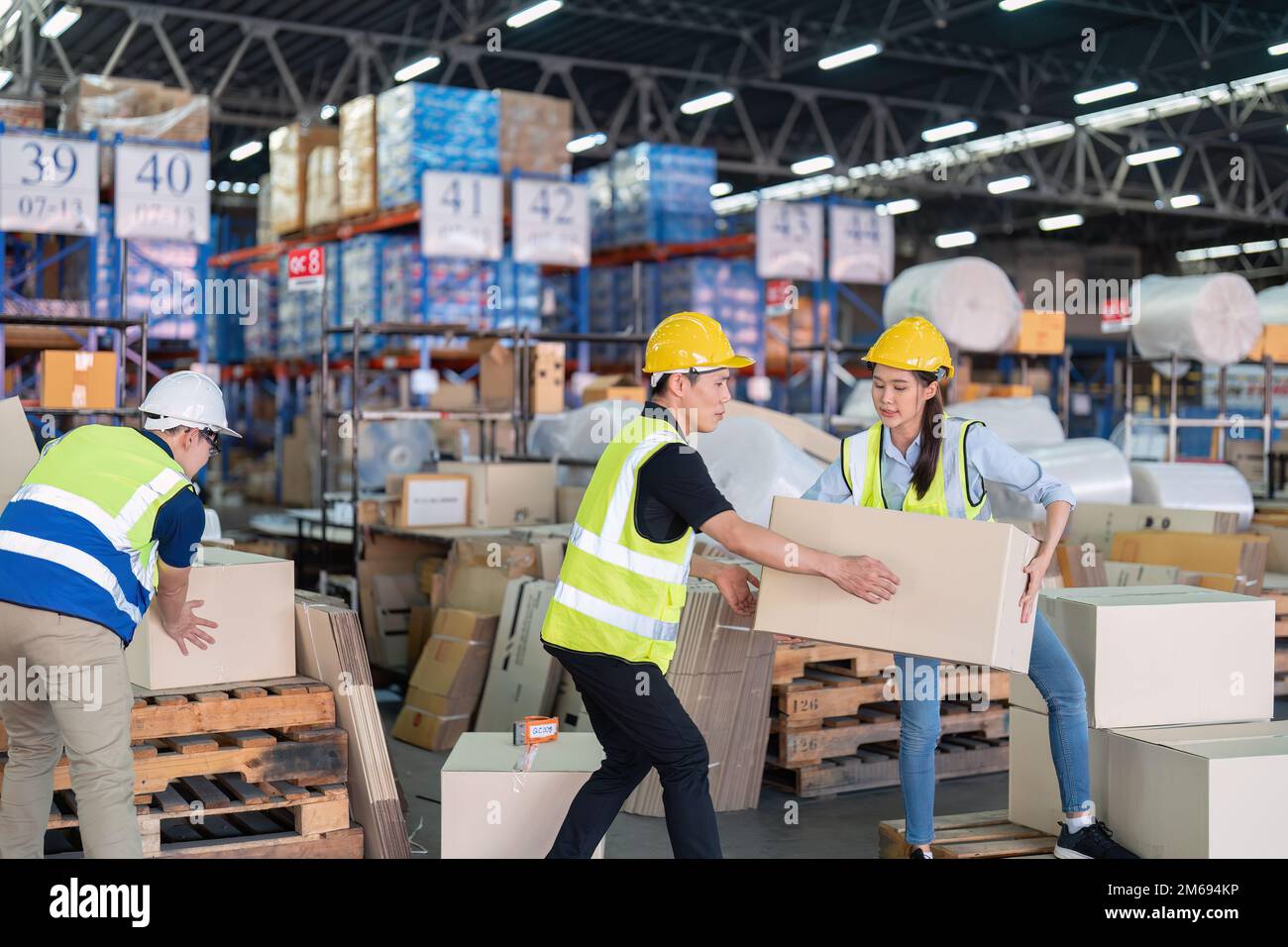 Staff in large storage warehouse together packing goods and carry ...