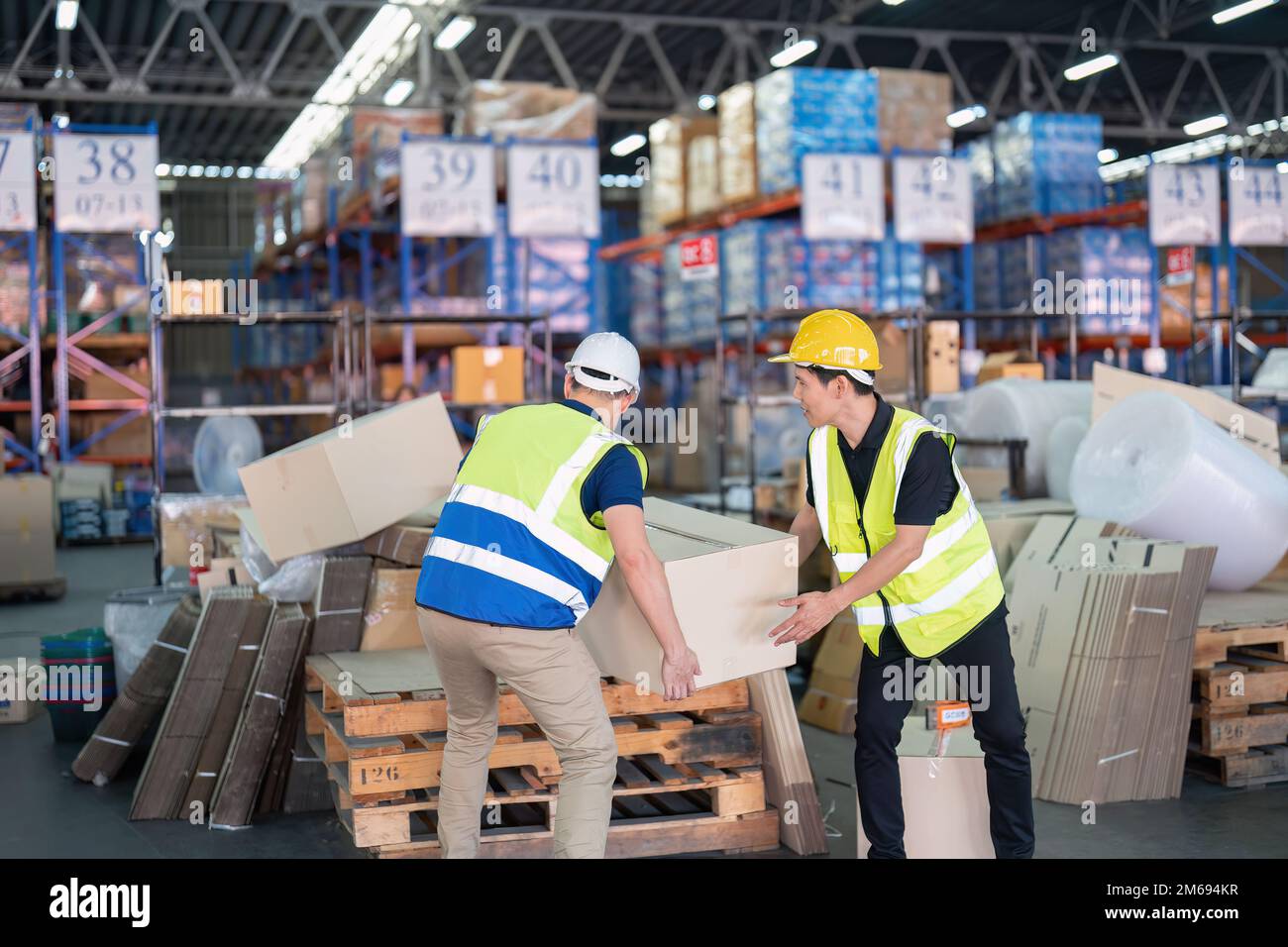 Staff in large storage warehouse together packing goods and carry ...