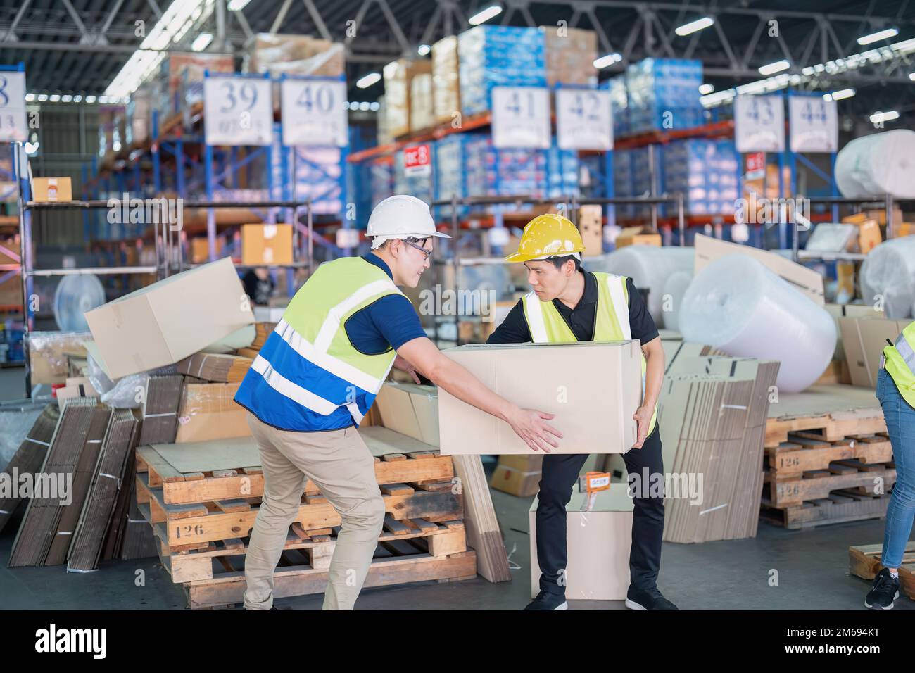 Staff in large storage warehouse together packing goods and carry ...