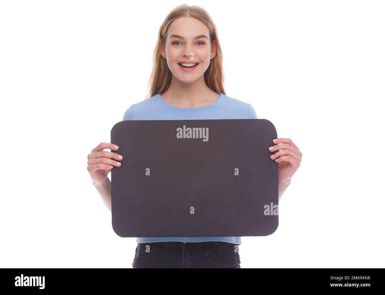 Vivacious young woman winking and laughing as she points at a blank ...