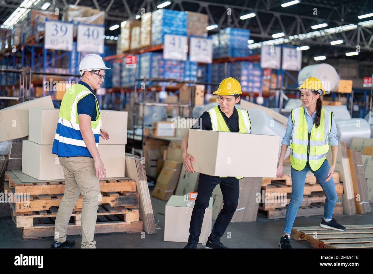 Staff in large storage warehouse together packing goods and carry ...