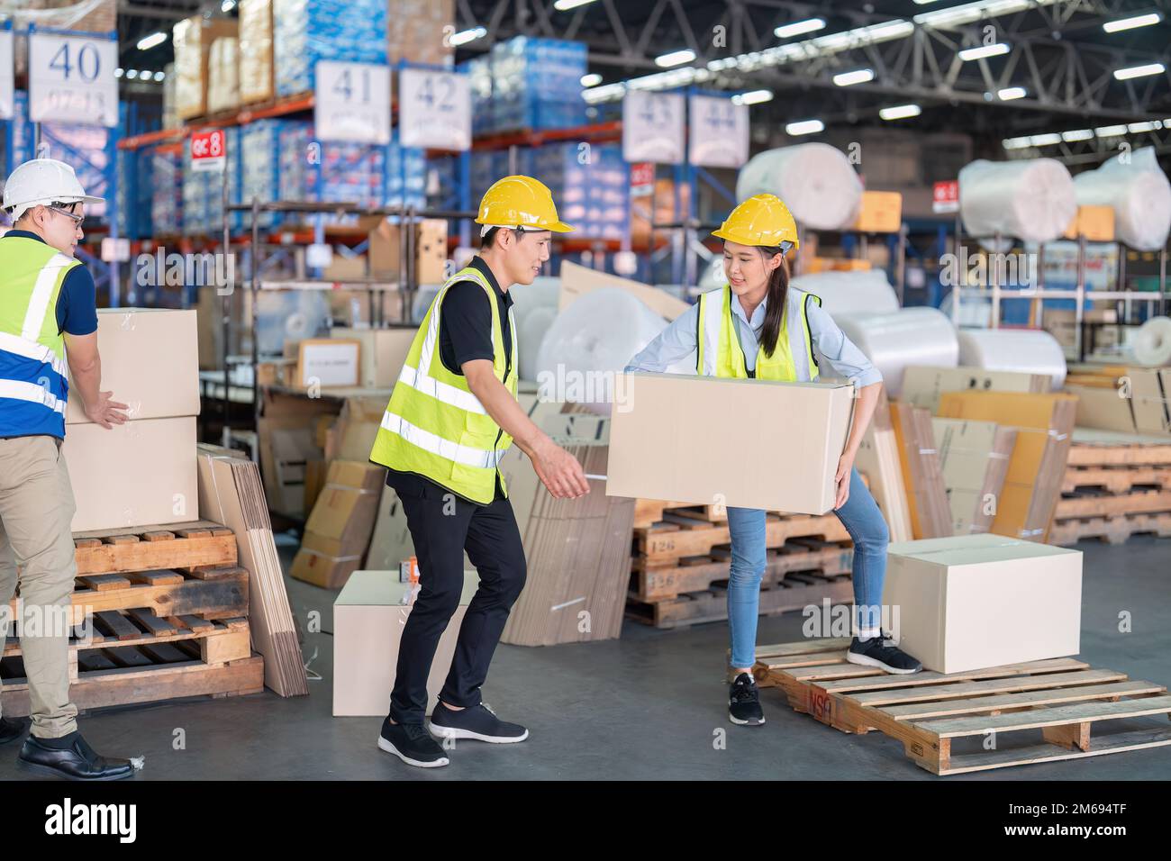 Staff in large storage warehouse together packing goods and carry ...
