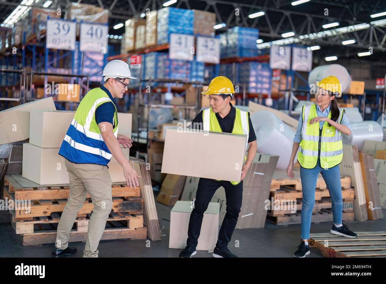 Staff in large storage warehouse together packing goods and carry ...