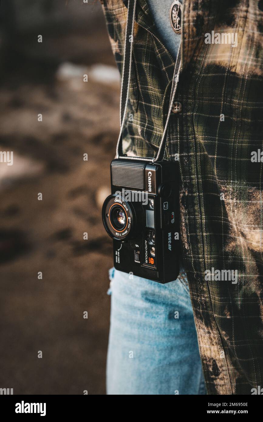 A woman wearing a flannel shirt with jeans and carrying a vintage canon ...