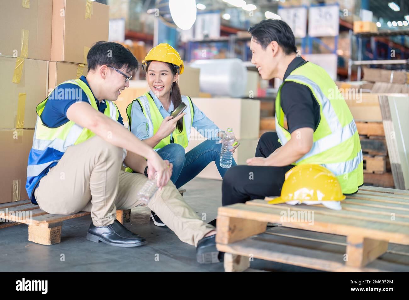Staff in large storage warehouse together sit back relax funny laughing ...
