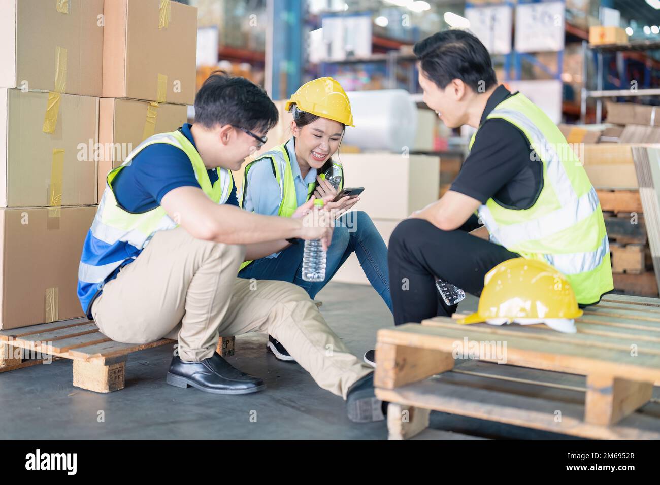 Staff in large storage warehouse together sit back relax funny laughing ...