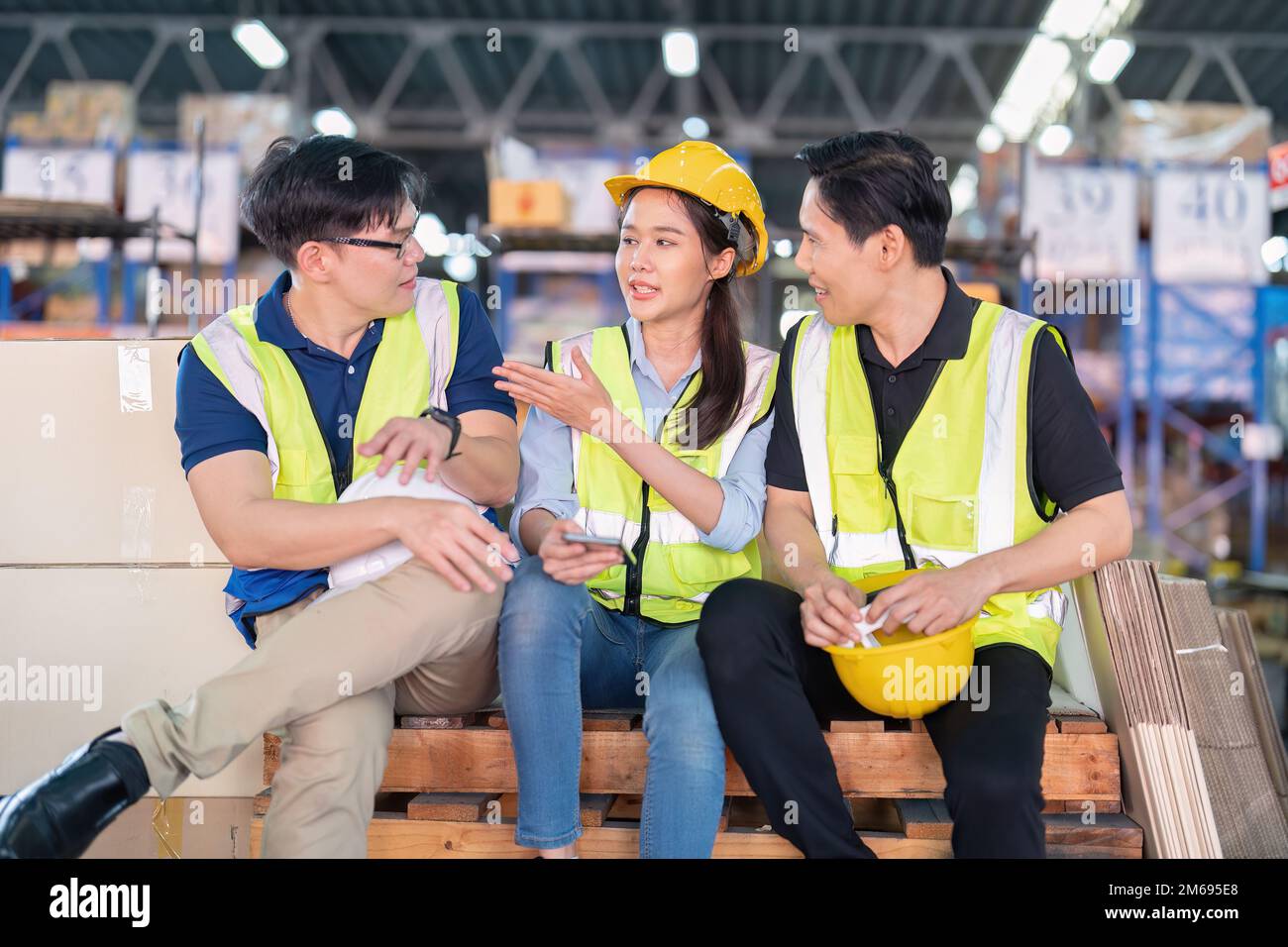 Staff in large storage warehouse together sit back relax funny laughing ...