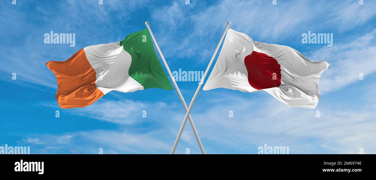 two crossed flags japan and Ireland waving in wind at cloudy sky ...