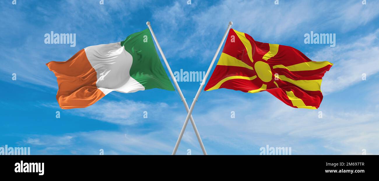two crossed flags Macedonia and Ireland waving in wind at cloudy sky ...