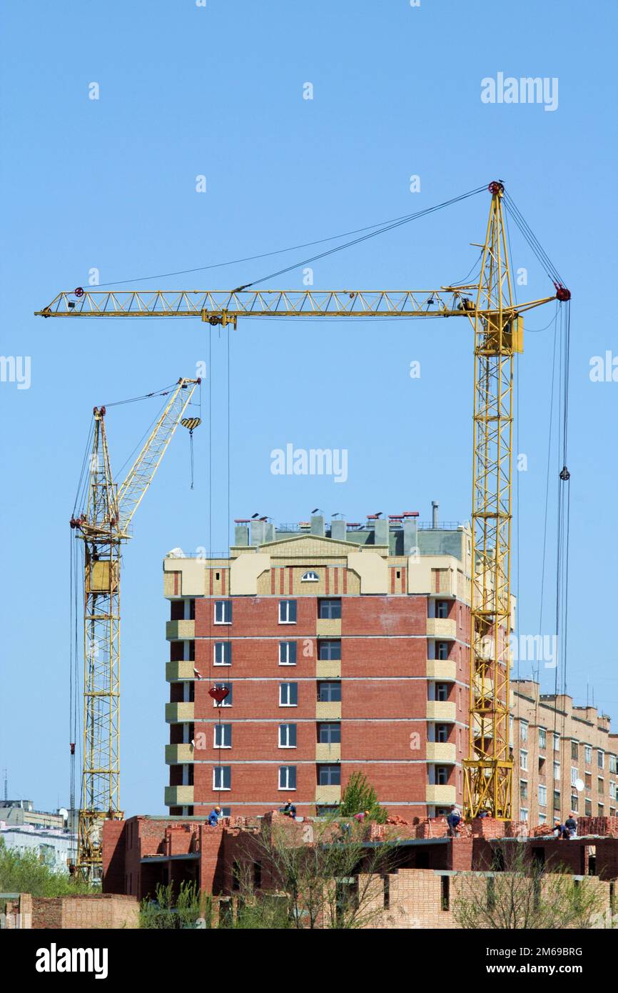 Two lifting cranes on building of the new house Stock Photo - Alamy