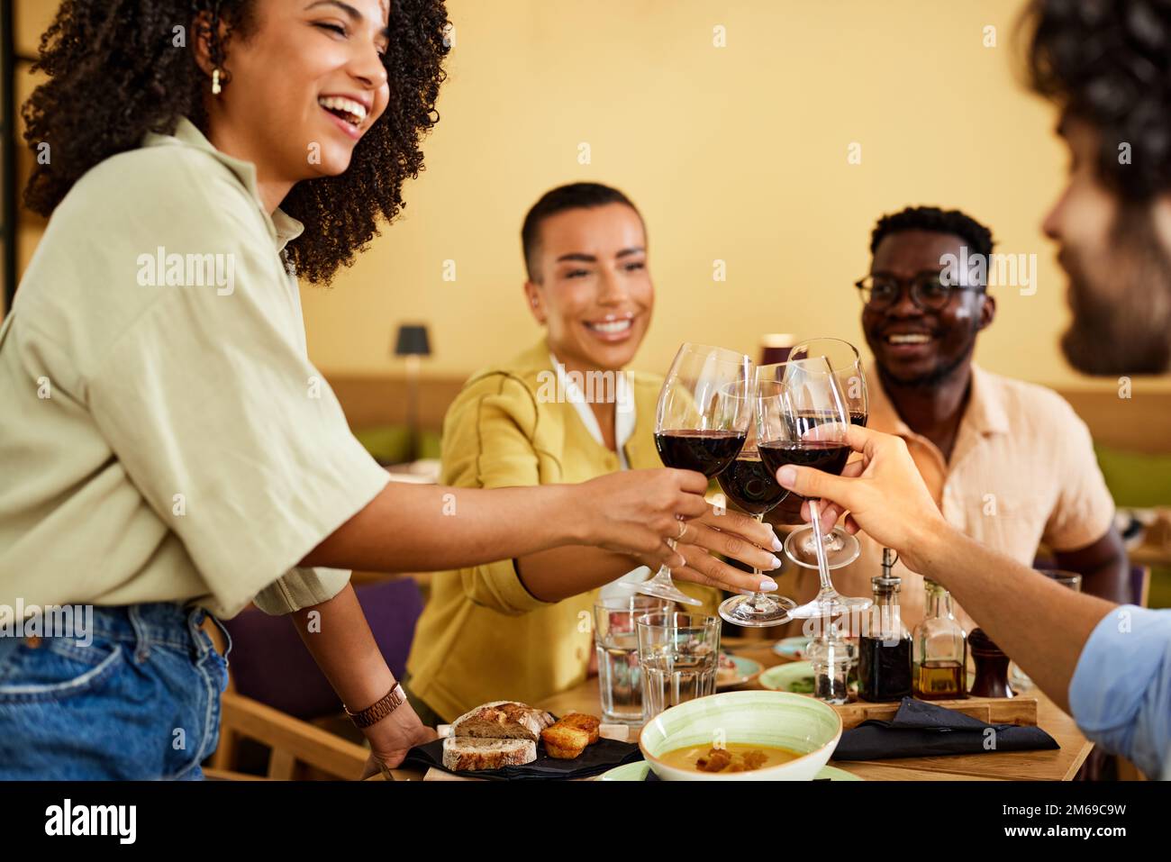 Multicultural friends toast with wine in the restaurant during dinner ...