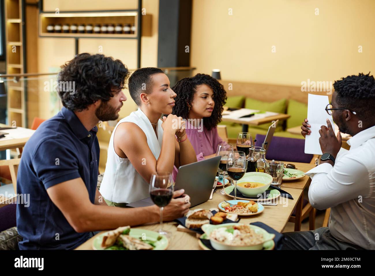 A group of casual businesspeople is sitting in a restaurant for a ...