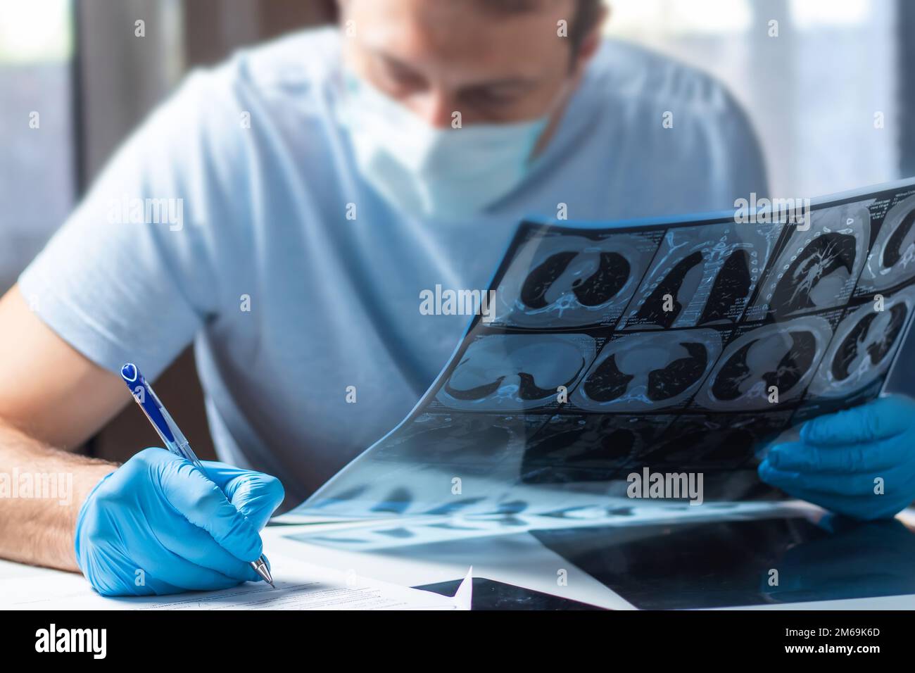 Doctor attentively examines the MRI scan of the patient and writes data ...