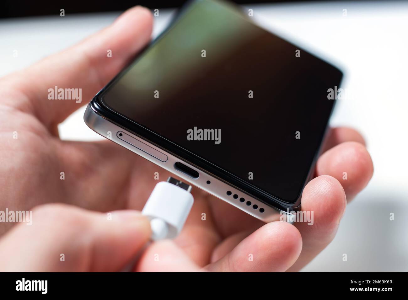 Charging a smartphone via a USB cable and a power supply. A black ...