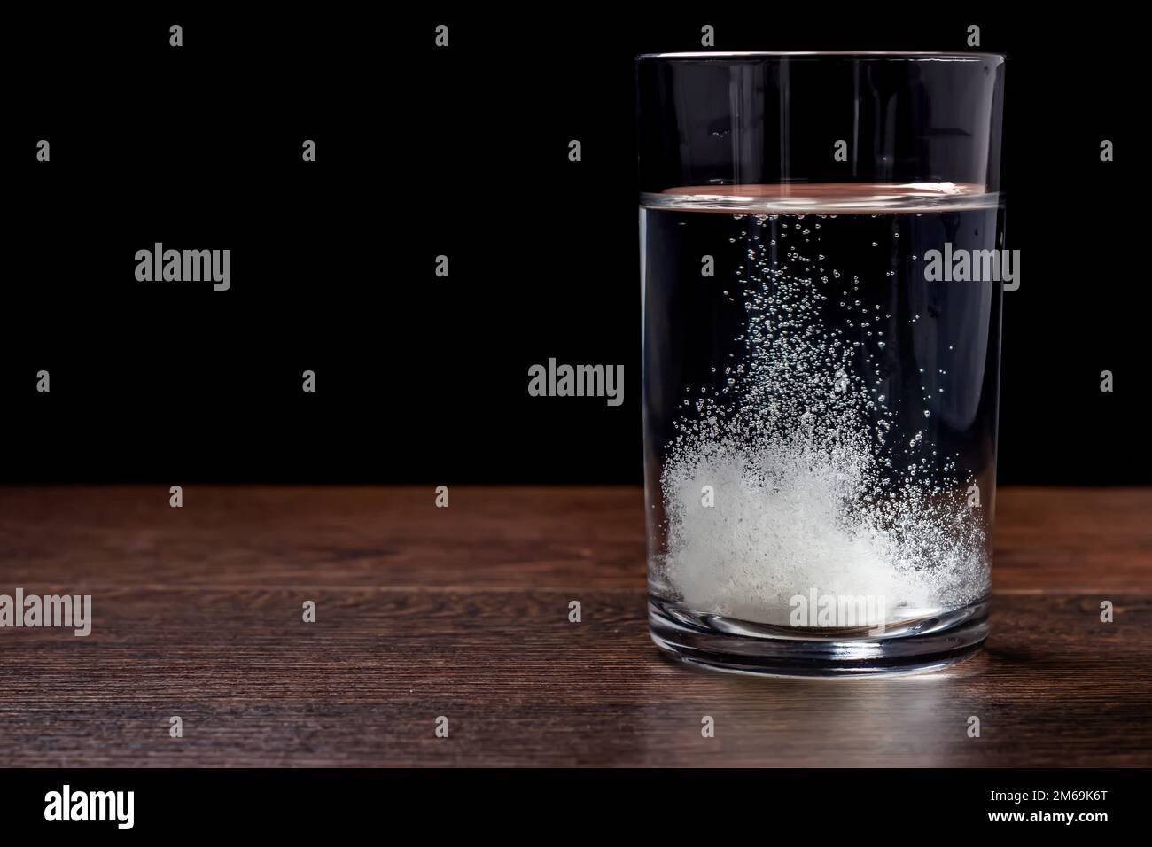 Effervescent tablet in a glass of water close-up on a black background ...