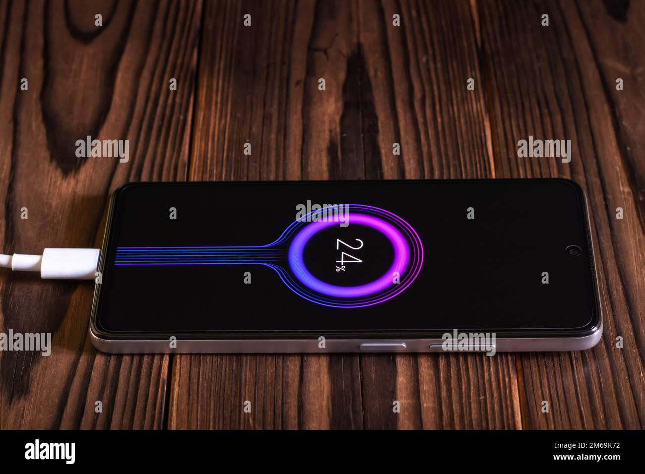 Mobile smart phones charging on wooden desk Stock Photo - Alamy
