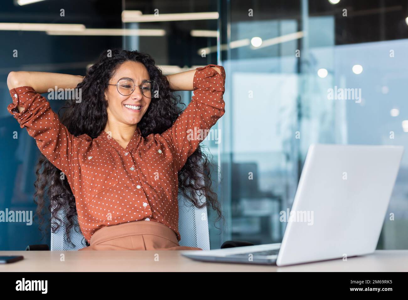 Happy and smiling successful hispanic business woman finished work satisfied with work result ...