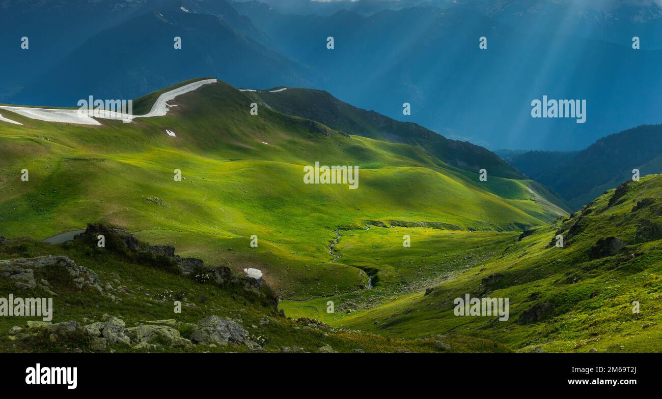 Green river valley in beams of evening sun. Caucasus mountains ...