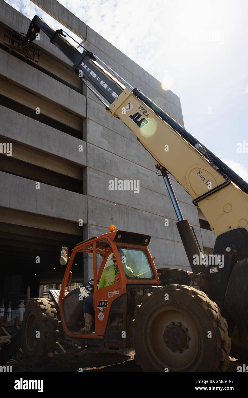 Construction workers with Nan Inc. use an electric boom lift while ...