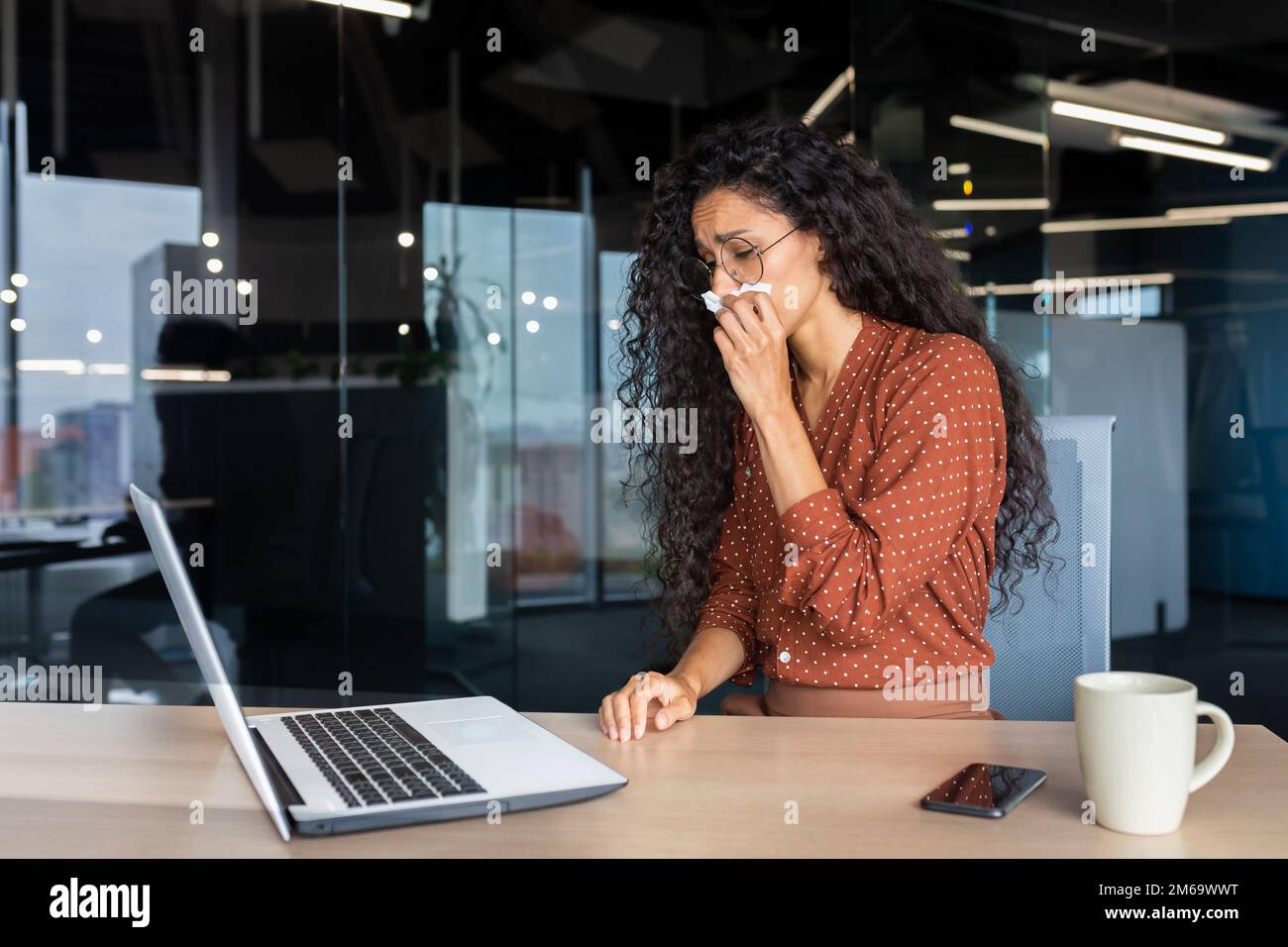 Sick woman working in office, hispanic woman having flu and cold ...